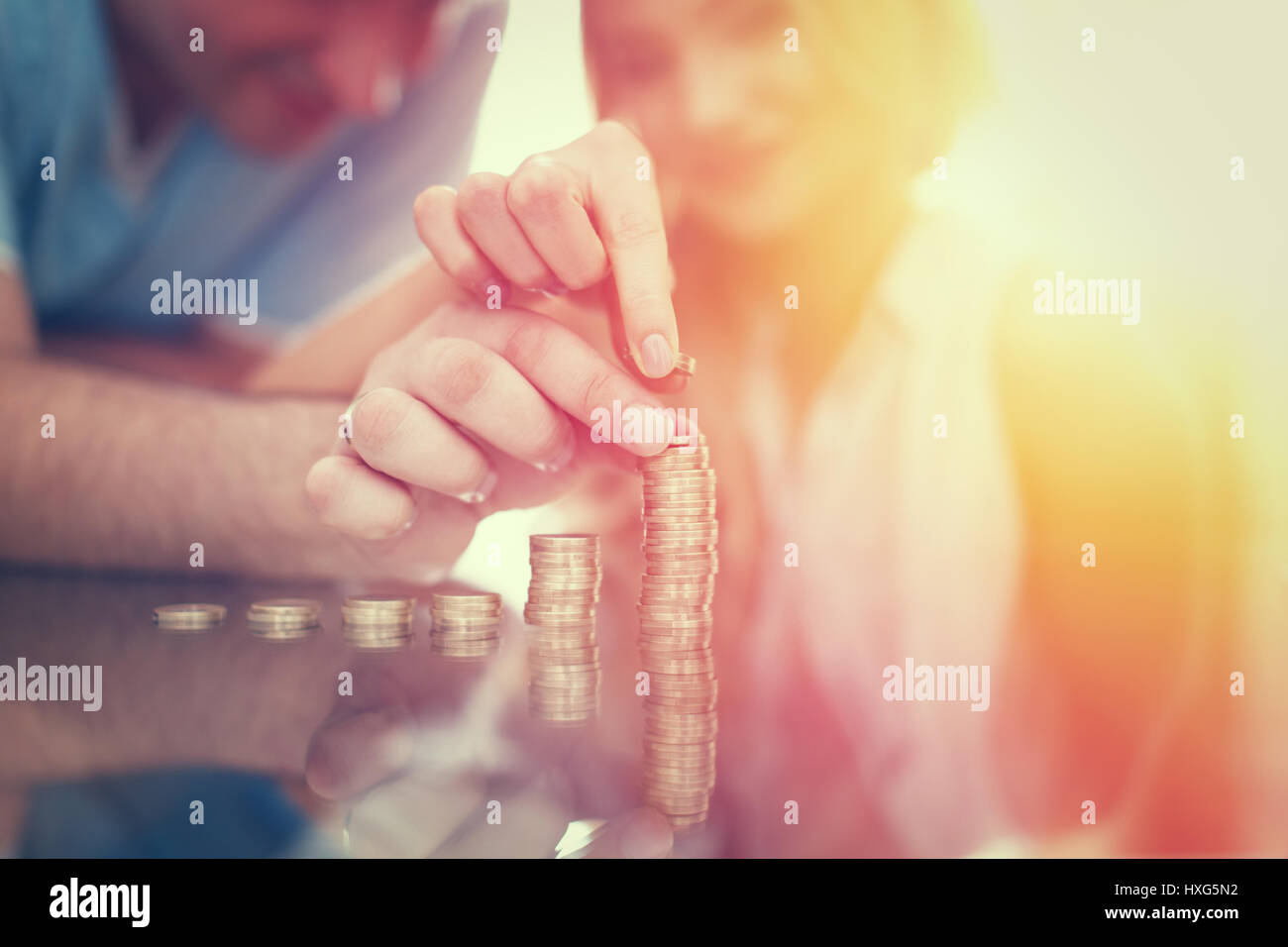 Young couple building money column from coins in sunset Stock Photo - Alamy