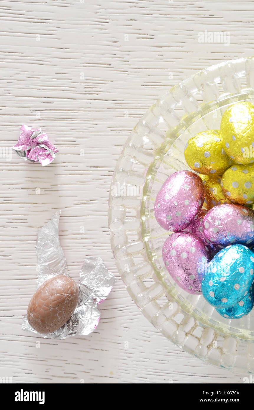 Chocolate egg foil wrapper and chocolate egg beside a glass bowl with ...
