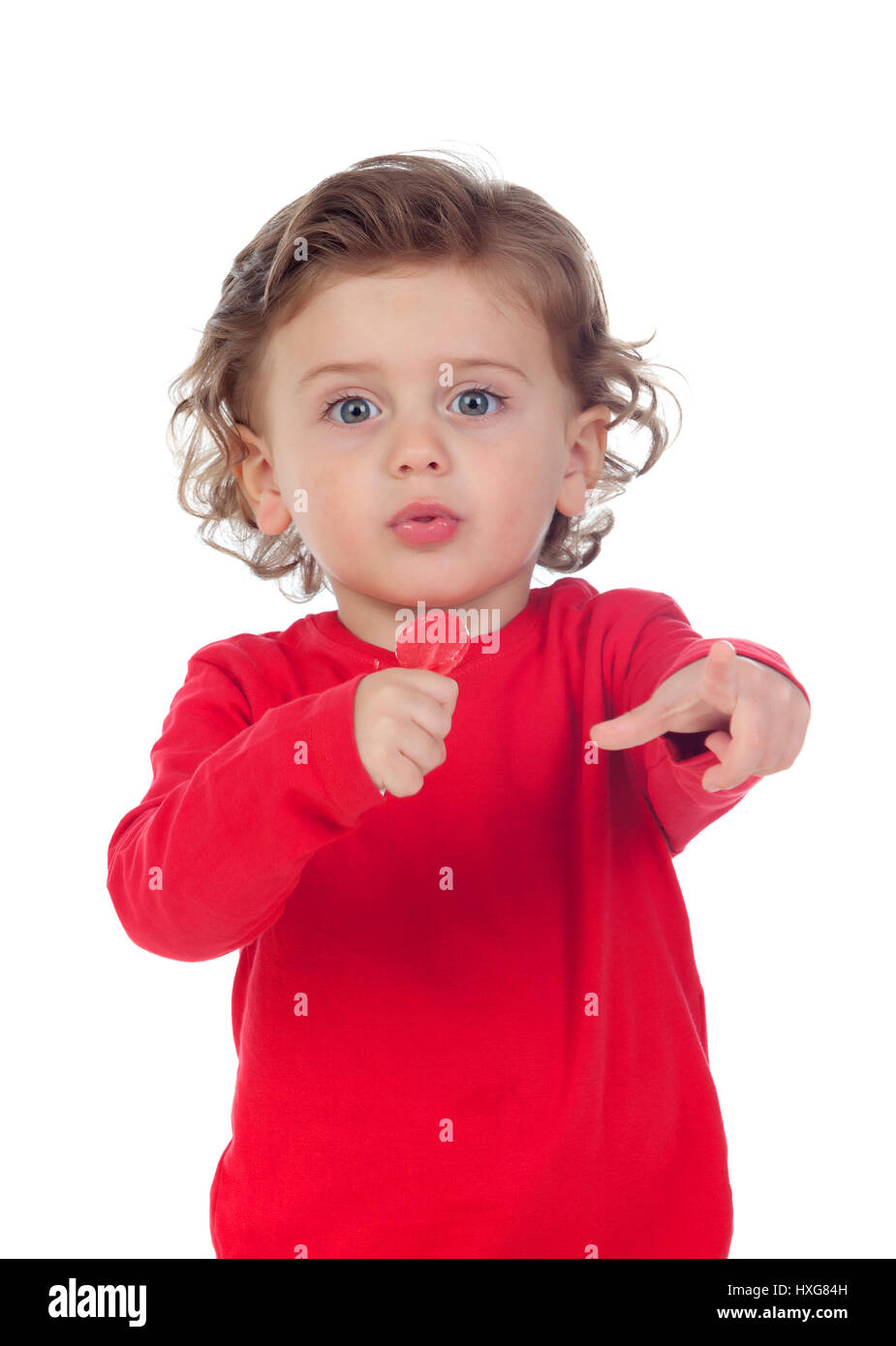 Adorable baby eating a lollipop and pointing with his finger isolated ...