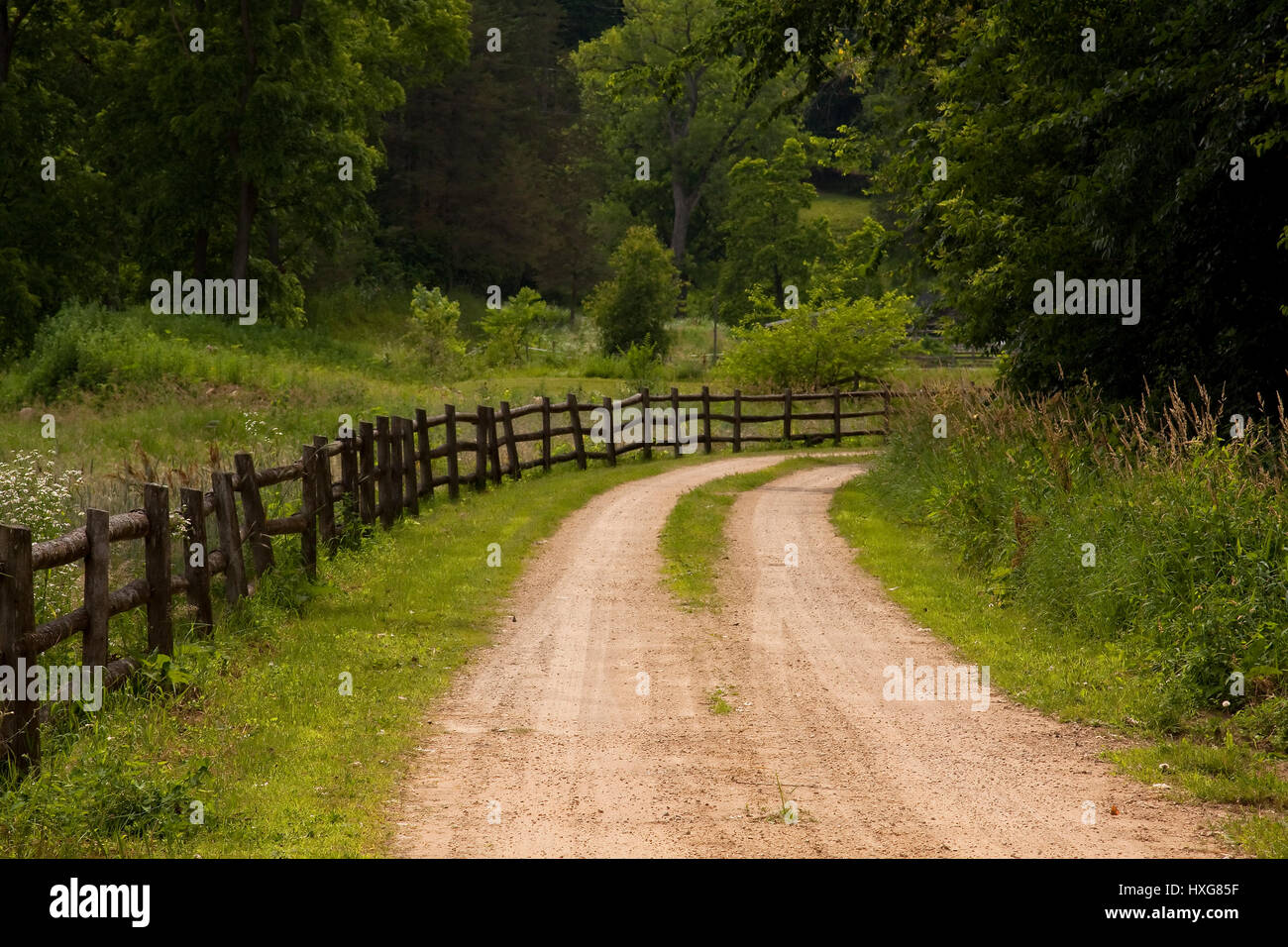 Rustic Country Road - An old road with a fence curving around some ...