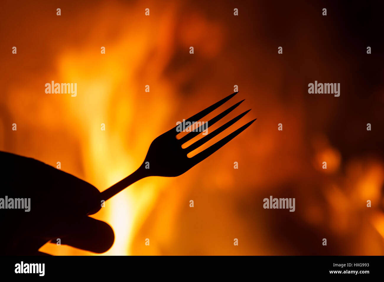 fork in hand against a background of fire,silhouettes, hell kitchen, a ...