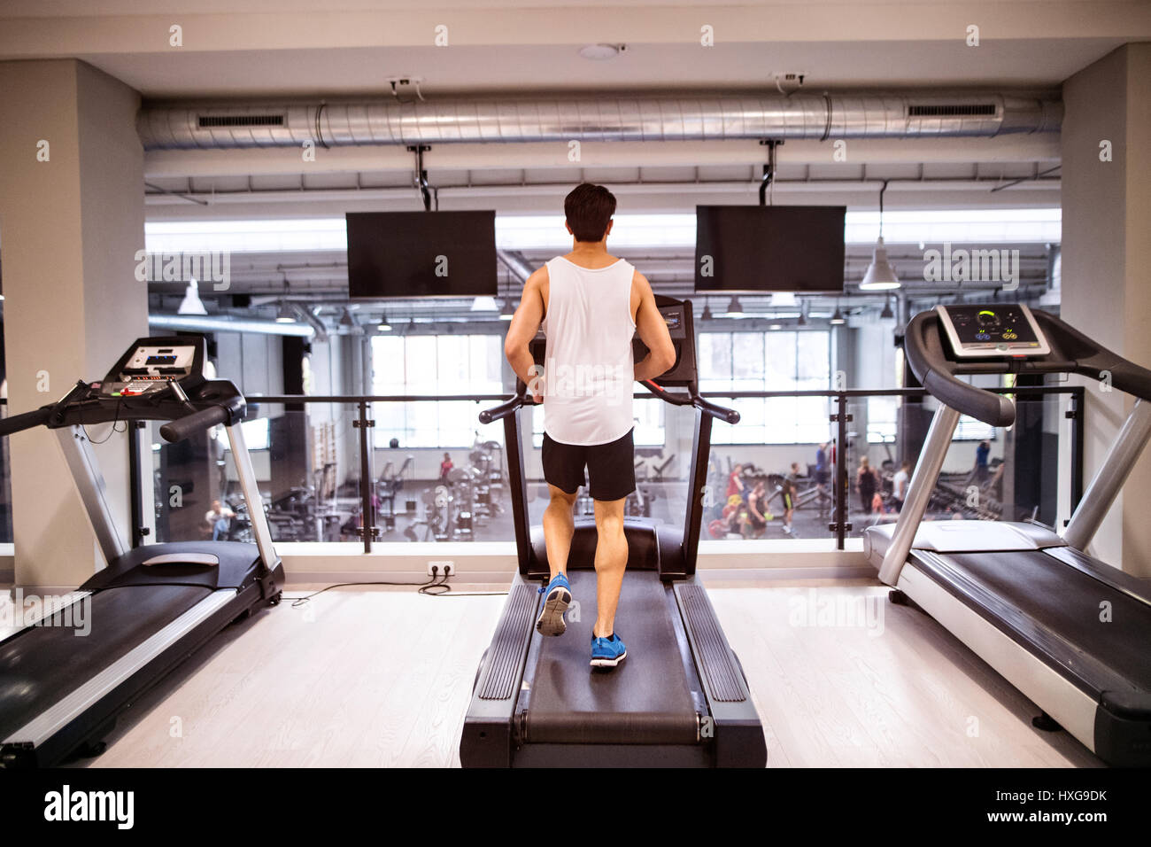 Young hispanic fitness man in sports clothing in gym doing cardio ...