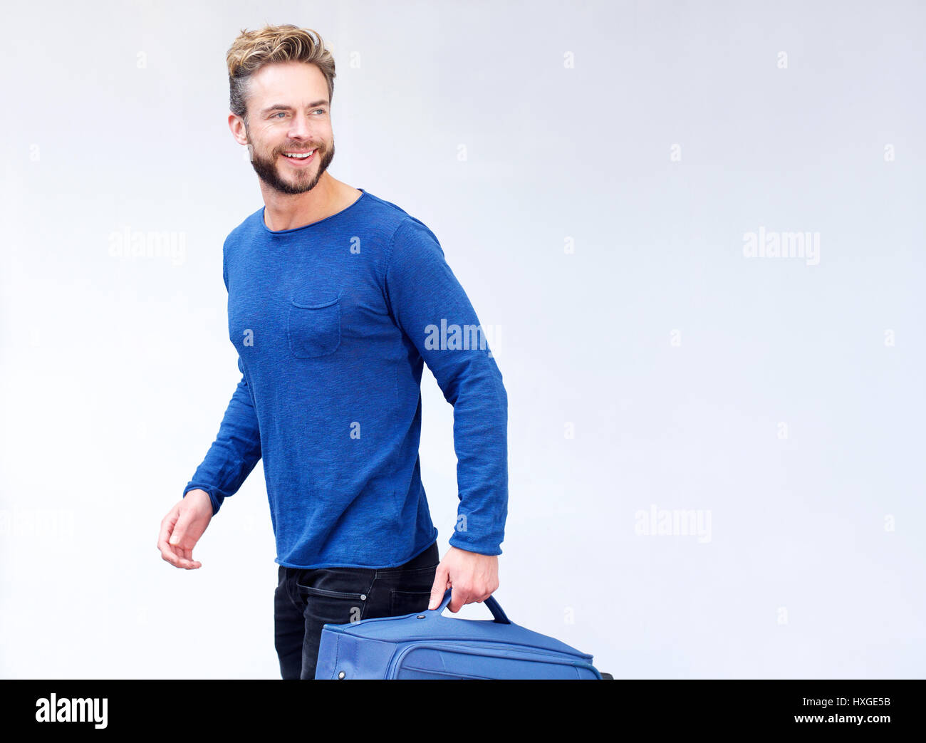 Portrait of a cool travel guy with bag smiling against white background ...