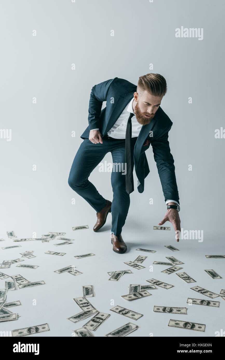 stylish businessman picking up dollar banknotes on grey Stock Photo - Alamy