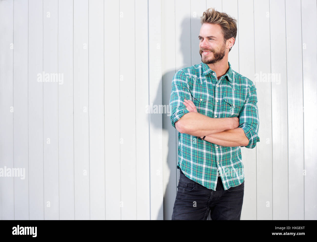 Portrait of a smiling modern man with beard standing against white ...