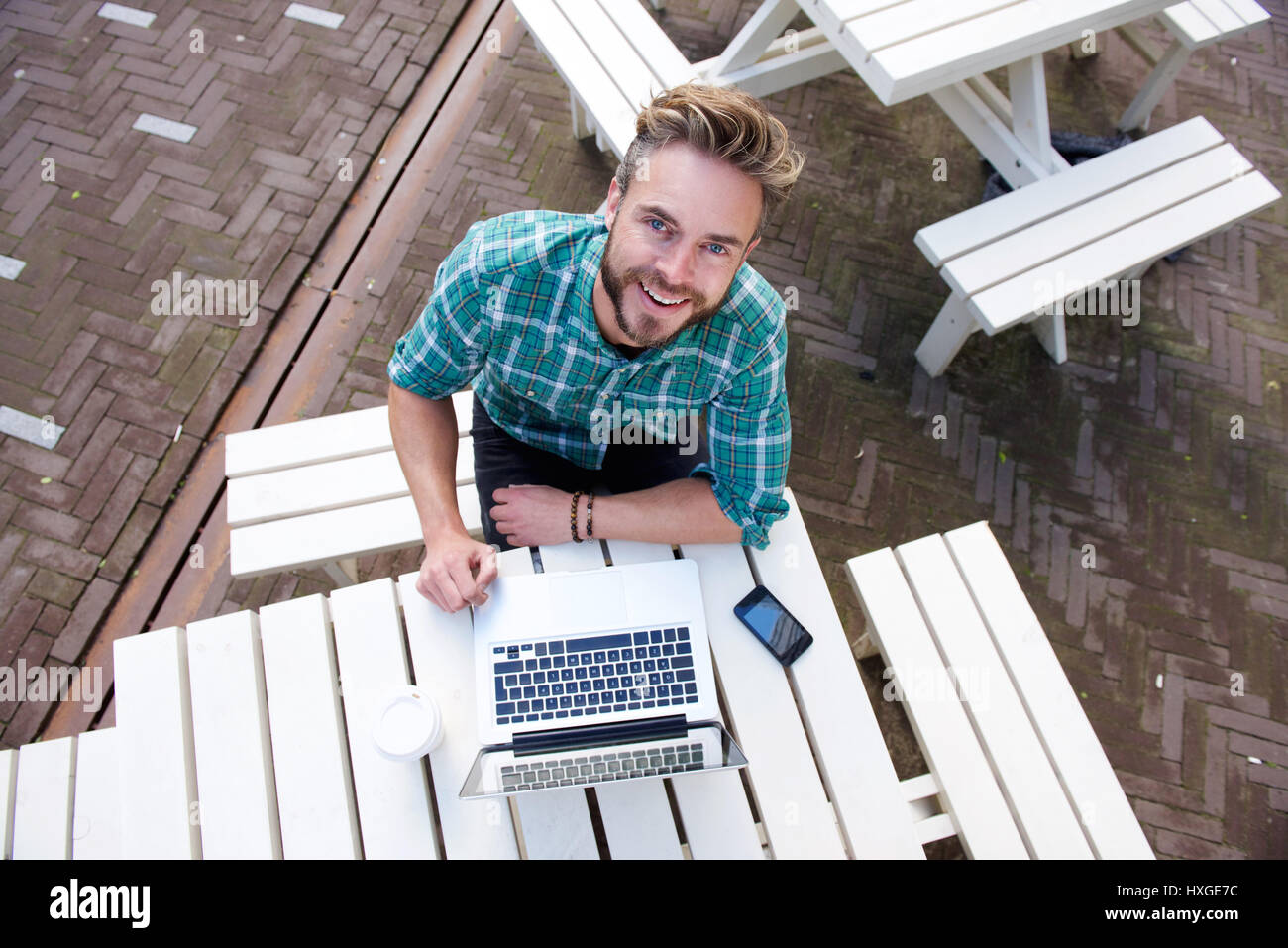 Portrait from above of a smiling man sitting outside with laptop Stock ...