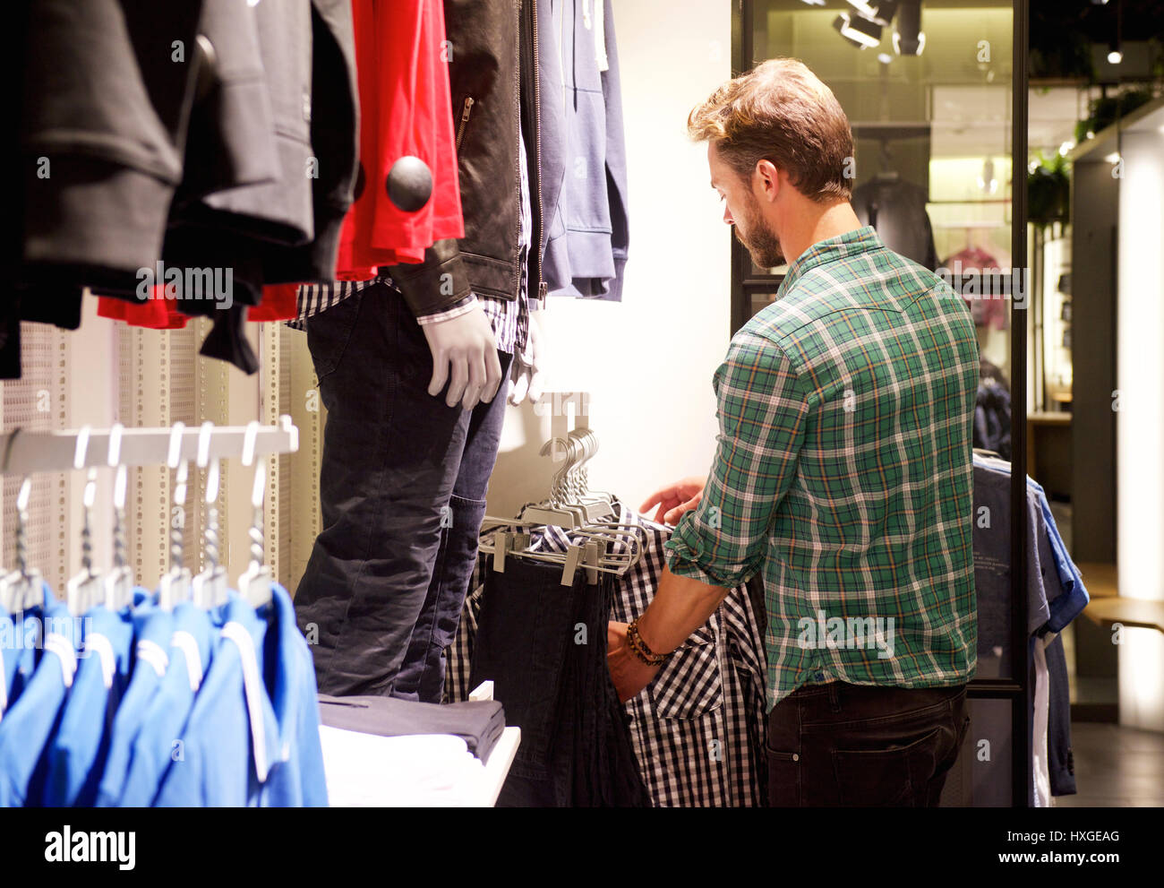 Portrait of a man looking at clothes in a store Stock Photo - Alamy