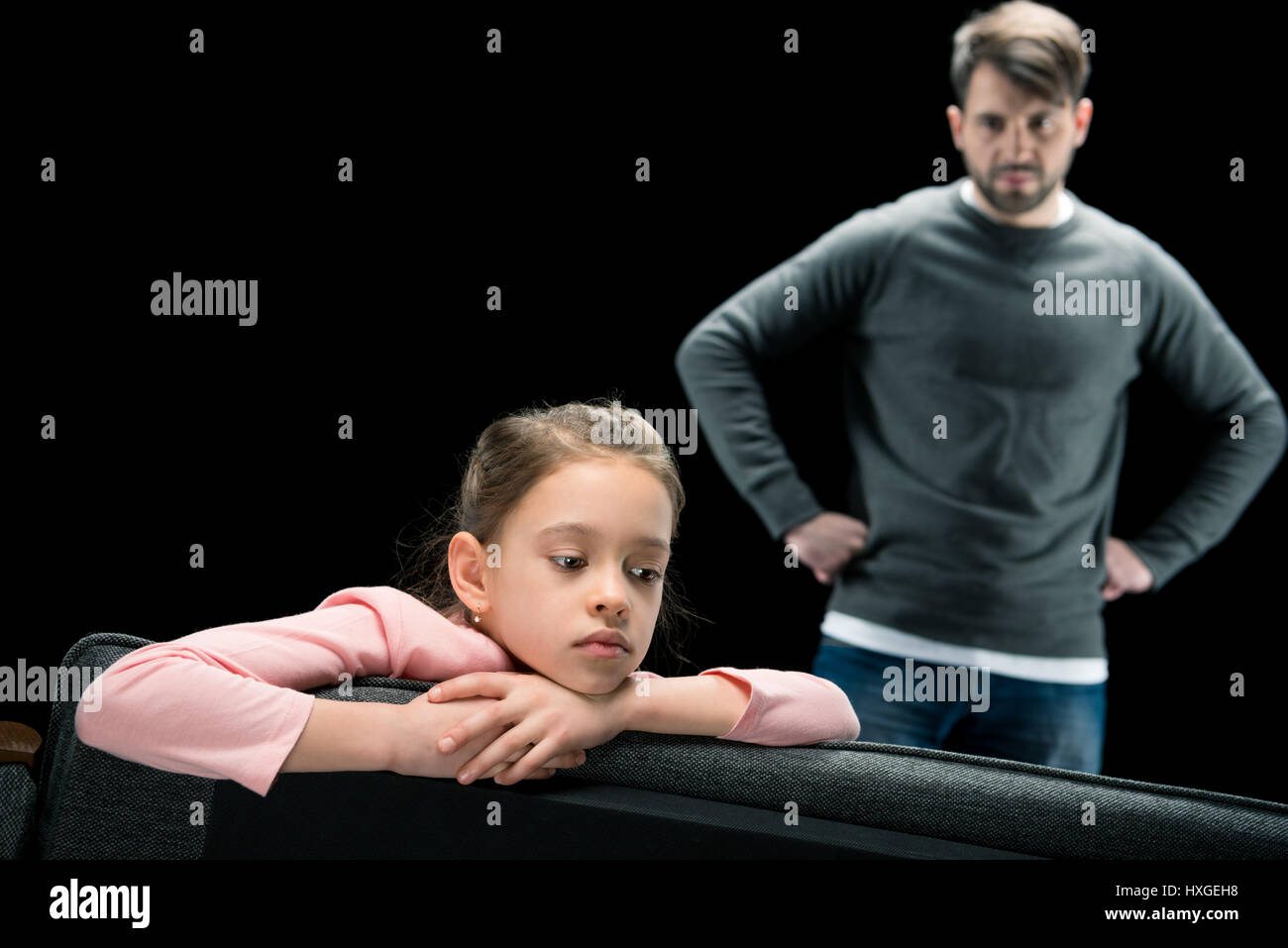 Aggressive father with hands on waist looking at upset daughter on ...