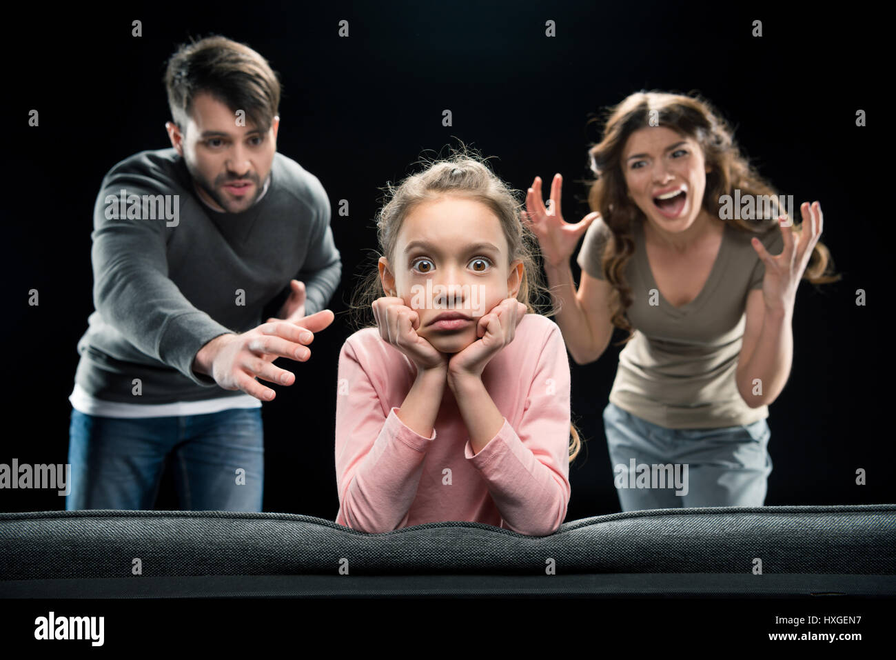 Emotional parents screaming at scared little daughter looking at camera ...