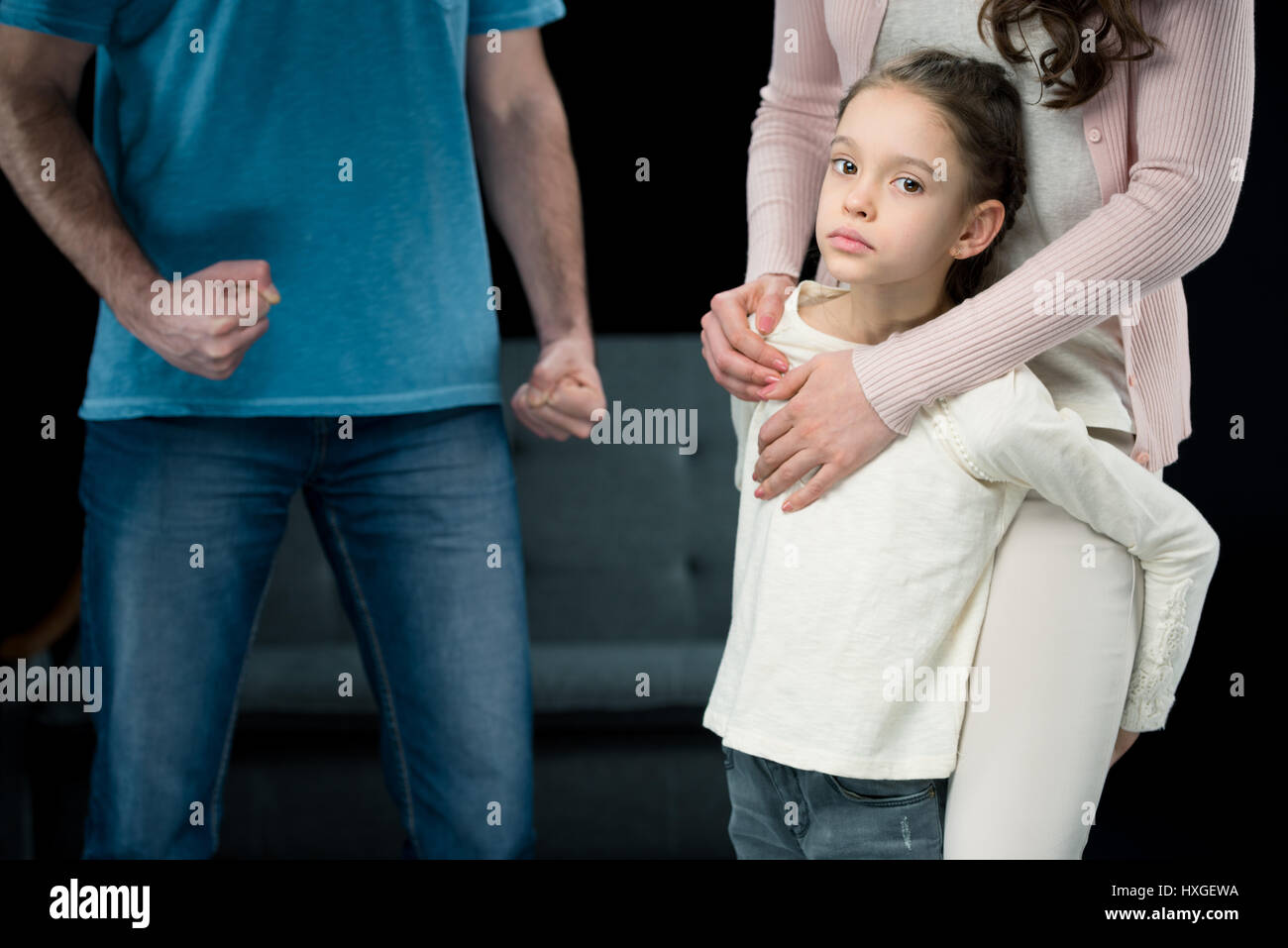 portrait of daughter hugging mother with aggressive father behind on ...
