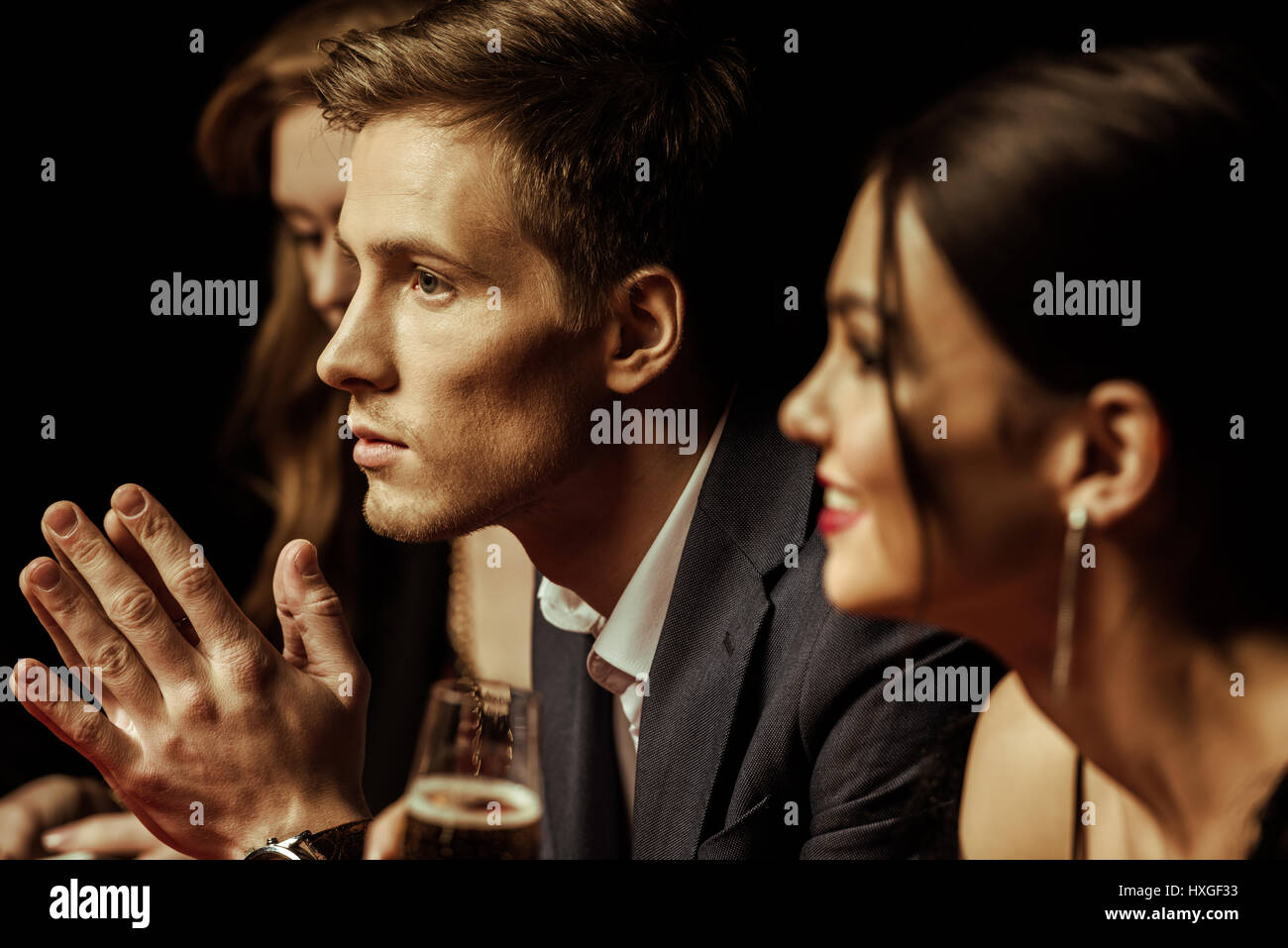 Side view of elegant young people drinking alcohol and looking away on ...