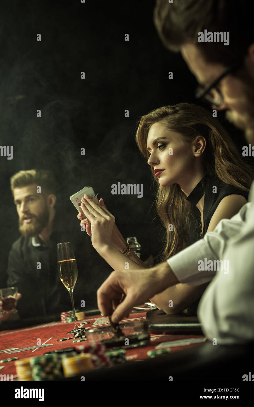 side view of concentrated woman playing poker with cards in hands Stock ...