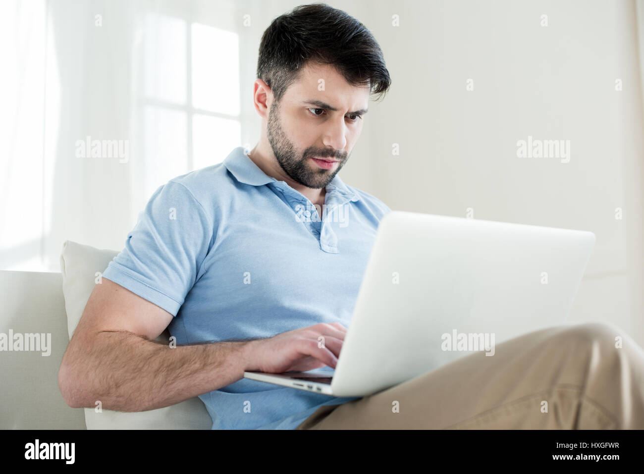 side view of concentrated man typing on laptop at home Stock Photo - Alamy