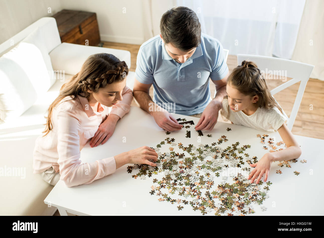 high angle view of focused parents and daughter playing with puzzles ...