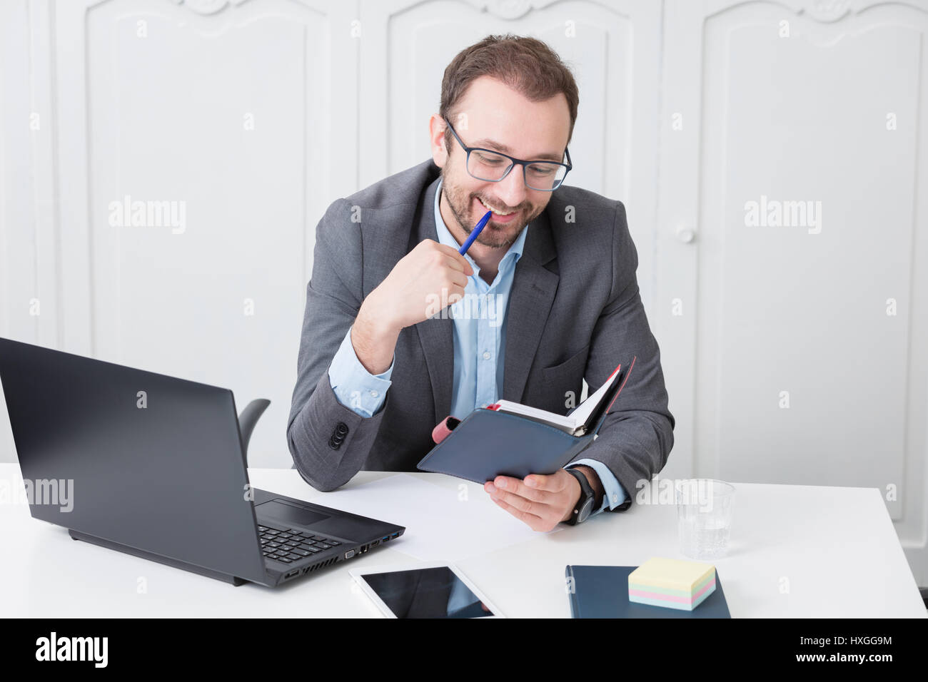 Cheerful business professional looking at meeting schedule notebook ...