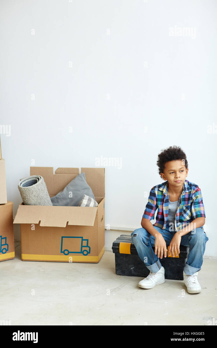 Boy sitting on tool-box in new flat Stock Photo - Alamy