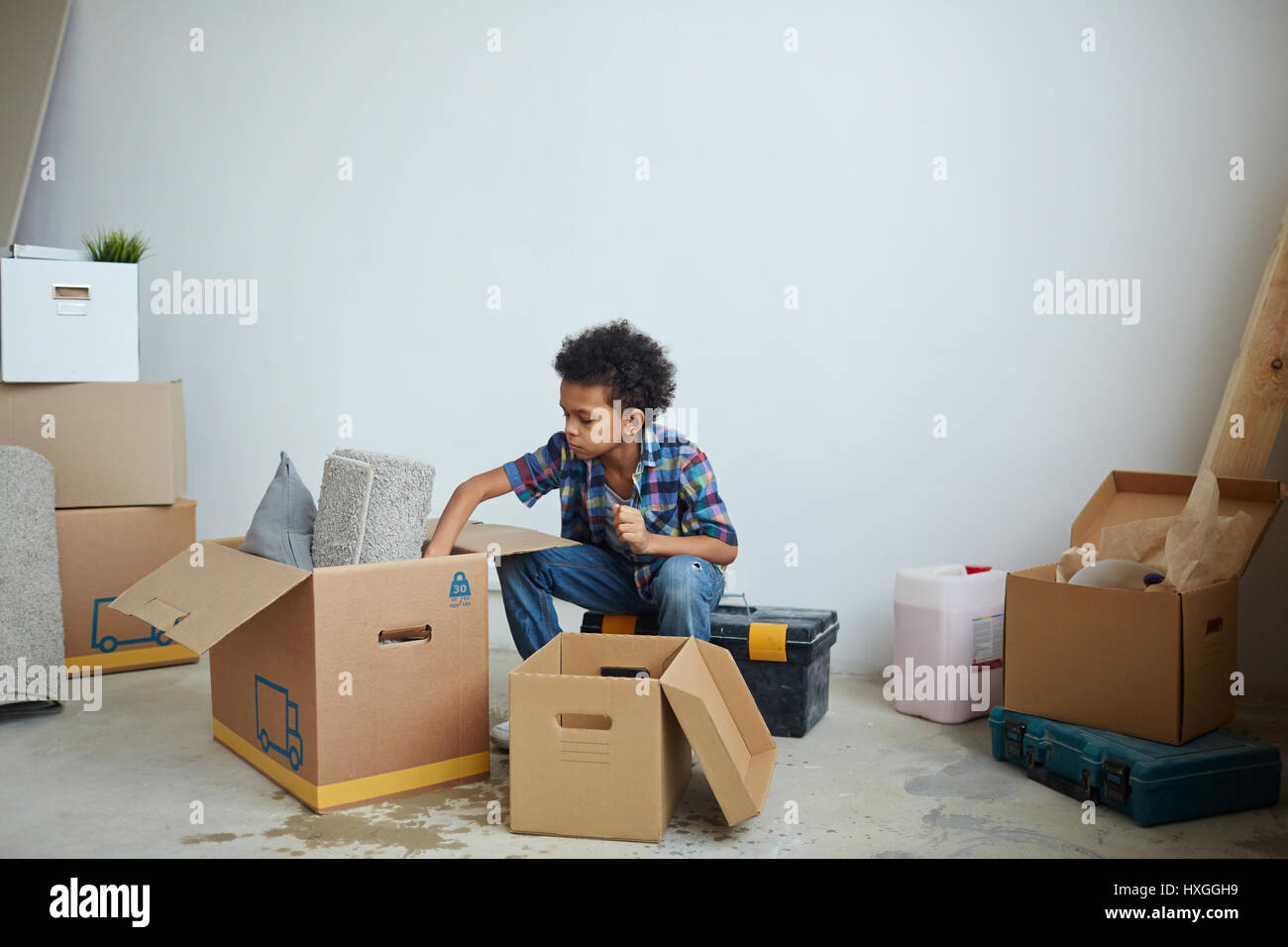 Youngster unpacking carton-boxes in new flat Stock Photo - Alamy