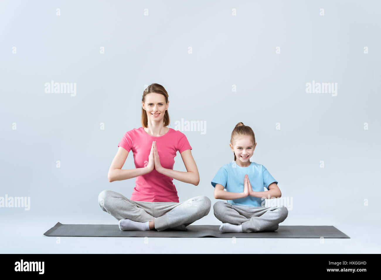 Smiling sporty mother and daughter practicing lotus yoga pose and ...