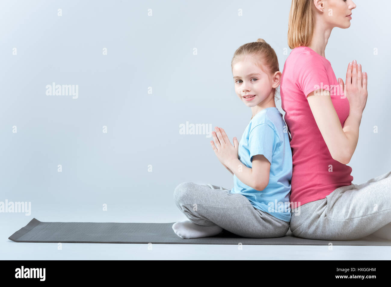 Side view of sporty mother and daughter practicing lotus yoga pose and ...