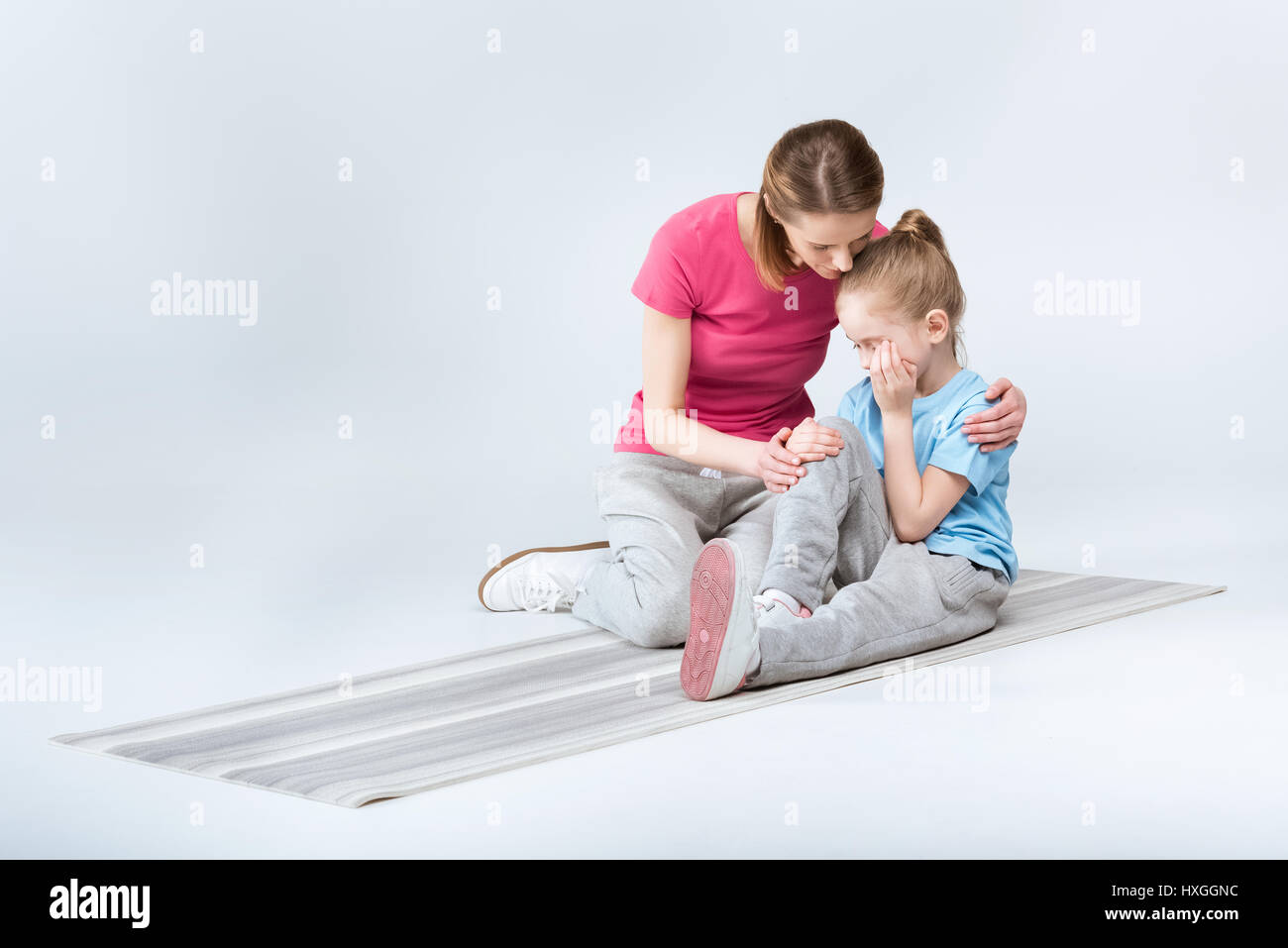 mother appeasing crying daughter during training on white Stock Photo ...