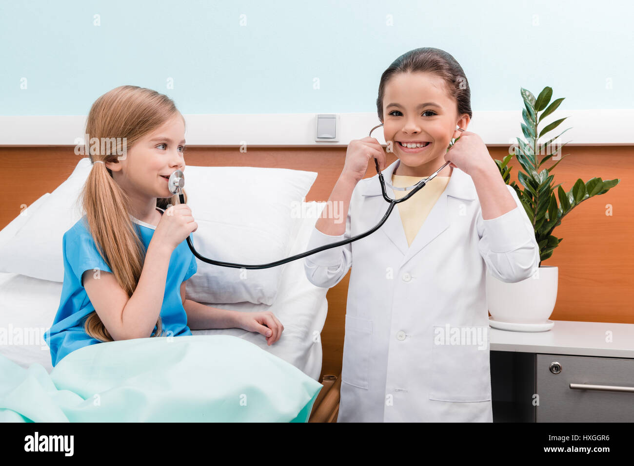 Smiling little girls playing doctor and patient with stethoscope in ...