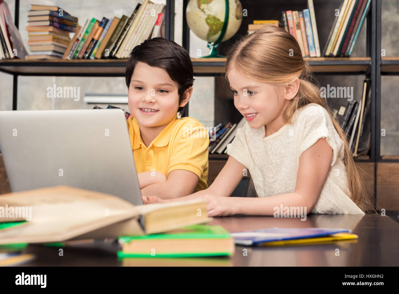 Cute smiling schoolchildren studying together and using laptop Stock ...