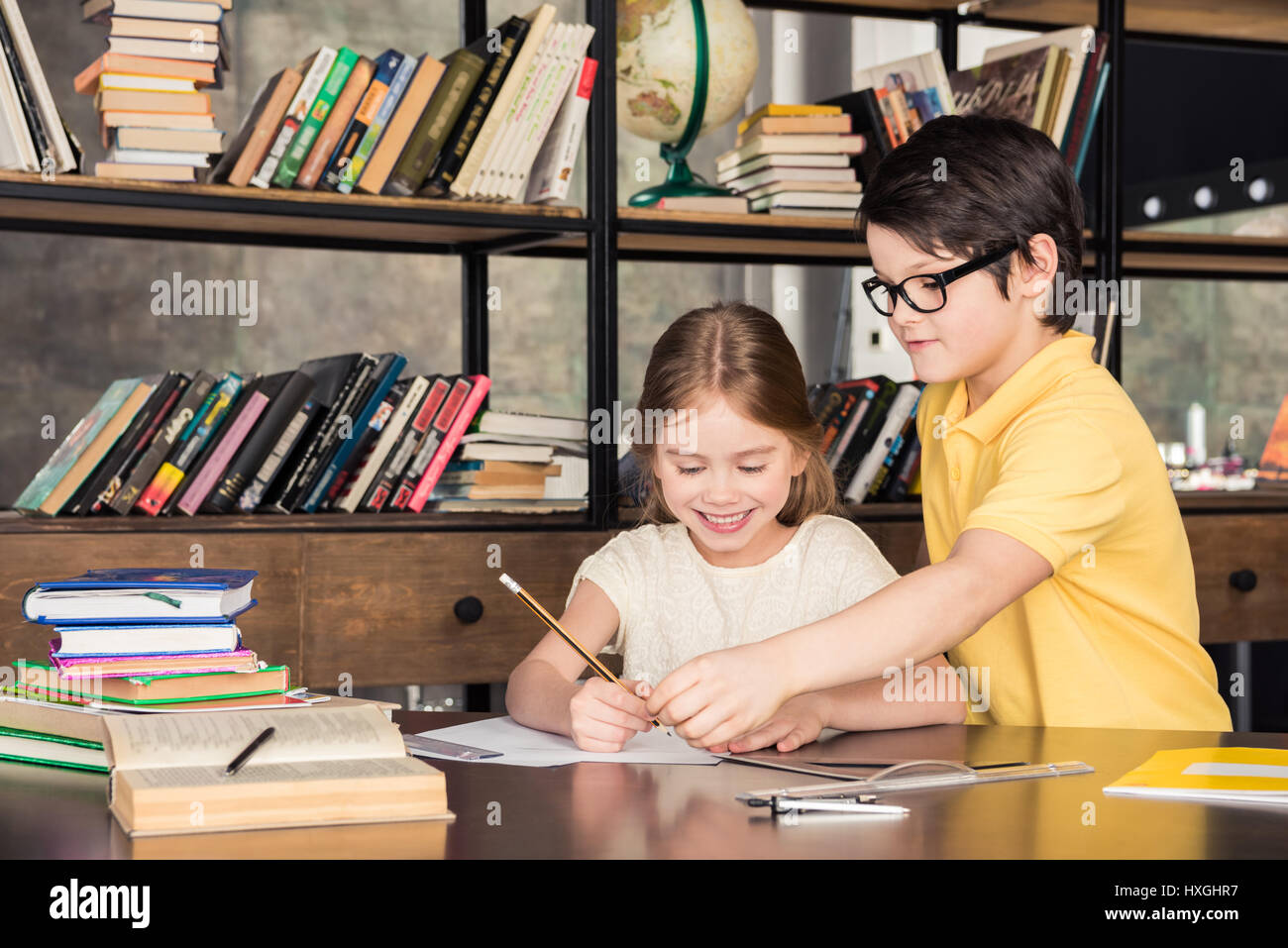 Schoolboy in eyeglasses helping classmate in doing homework Stock Photo ...
