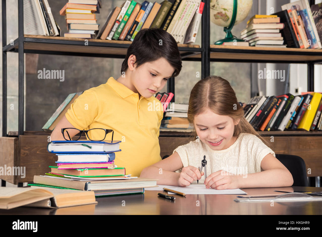 Cute little schoolchildren studying in library together Stock Photo - Alamy