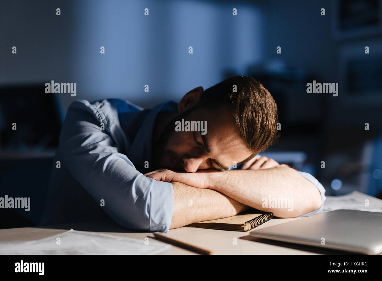 Portrait of exhausted man falling asleep at workplace in dark room late ...