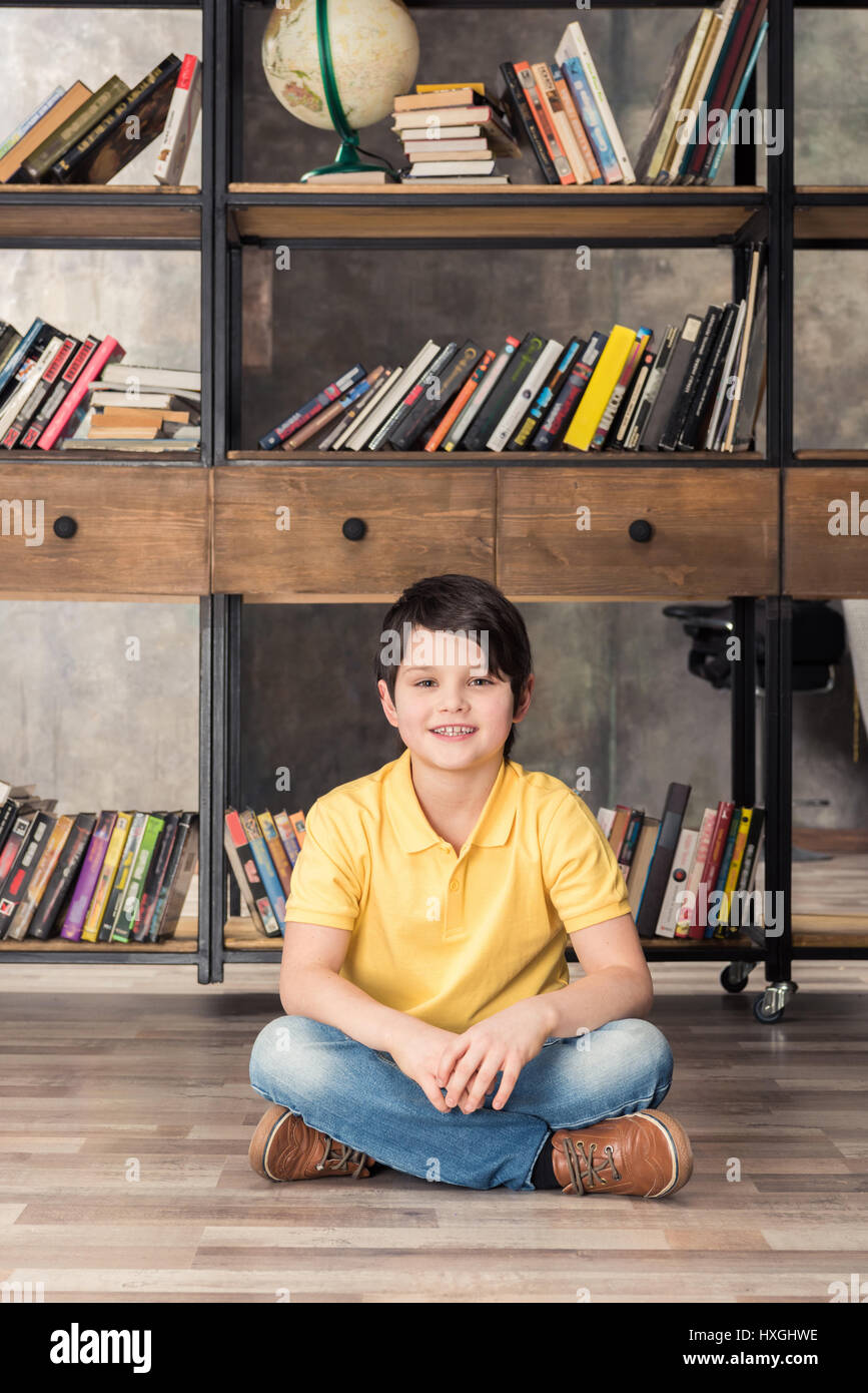 smiling boy sitting on floor in library Stock Photo - Alamy