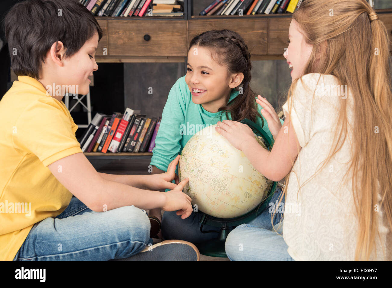 side view of cheerful classmates talking with globe in middle Stock ...