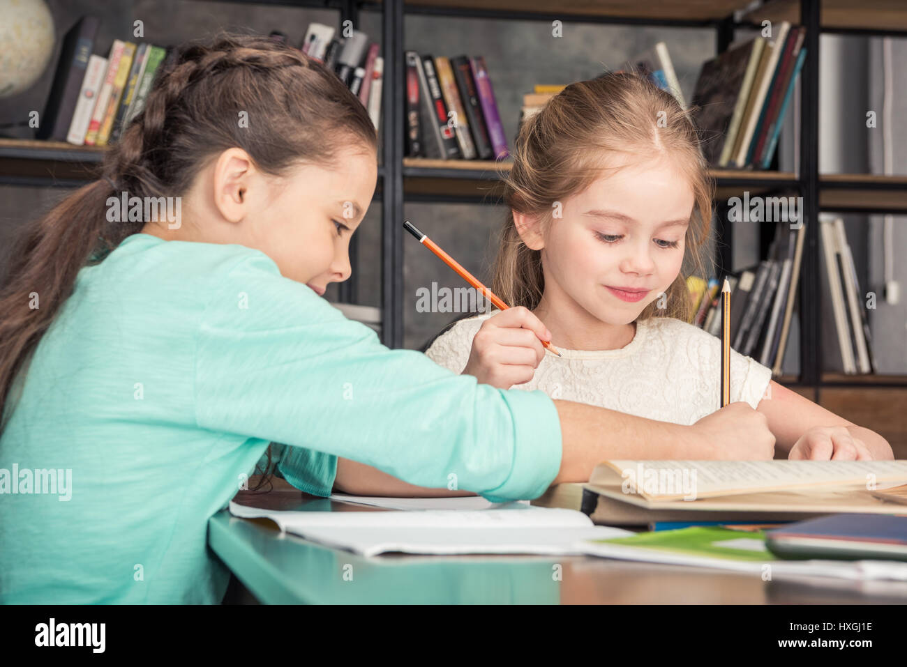 side view of smiling classmates doing homework together in library ...