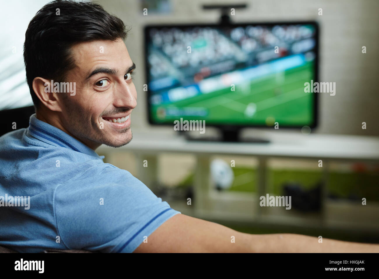 Portrait of handsome man smiling, turning to look at camera while ...