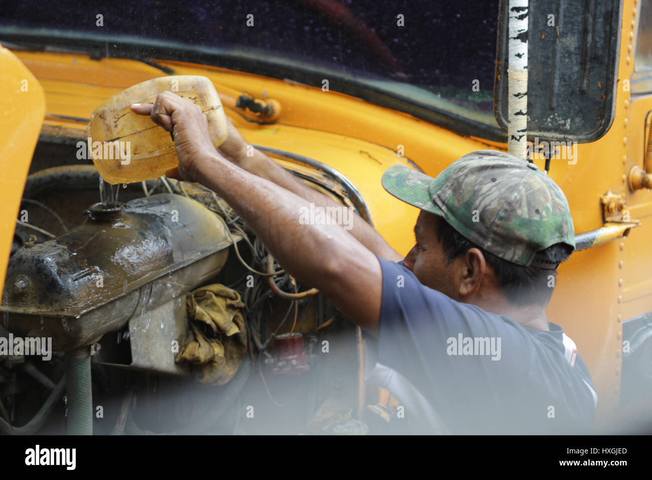 Bus driver is preparing the bus for a travel, filling gas, oil water ...