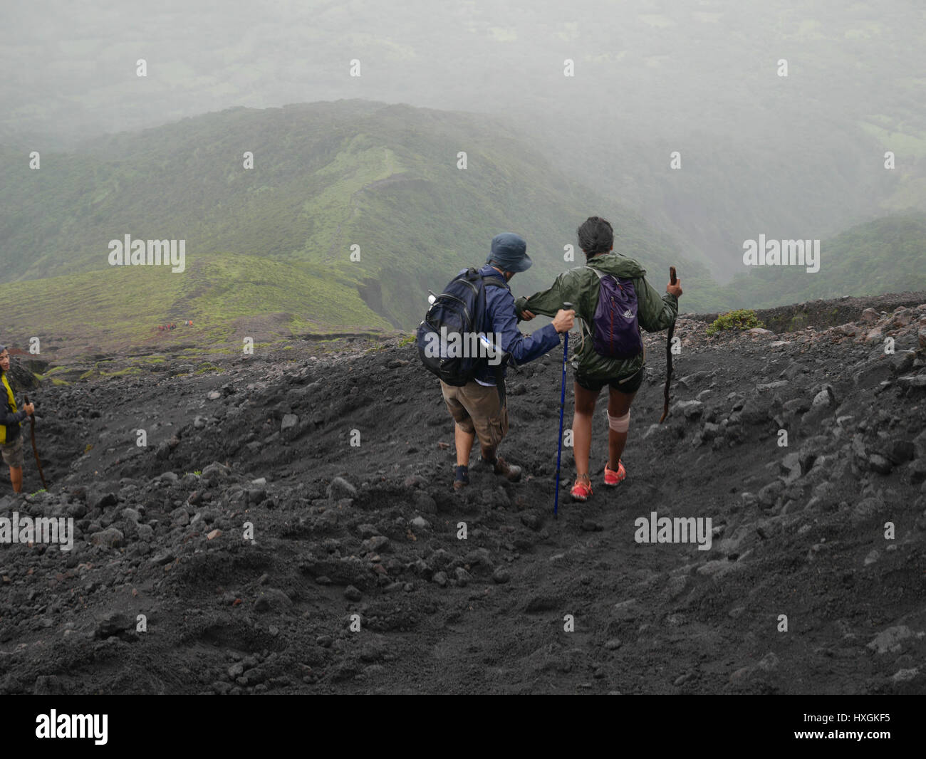 People hiking down from volcano, mountain in a group, Guide is helping ...
