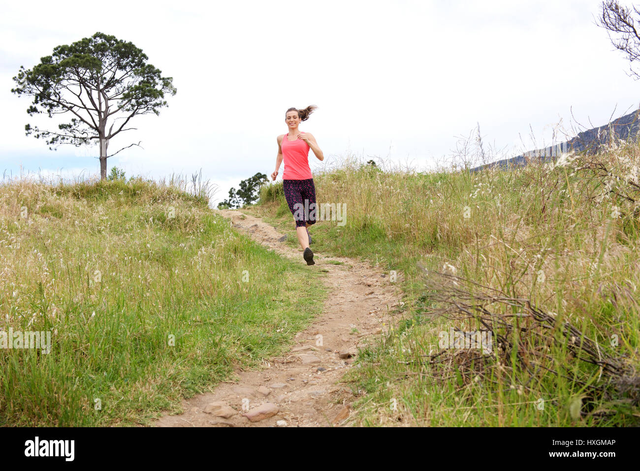 Full length portrait of athletic woman running on dirt path outdoors in ...