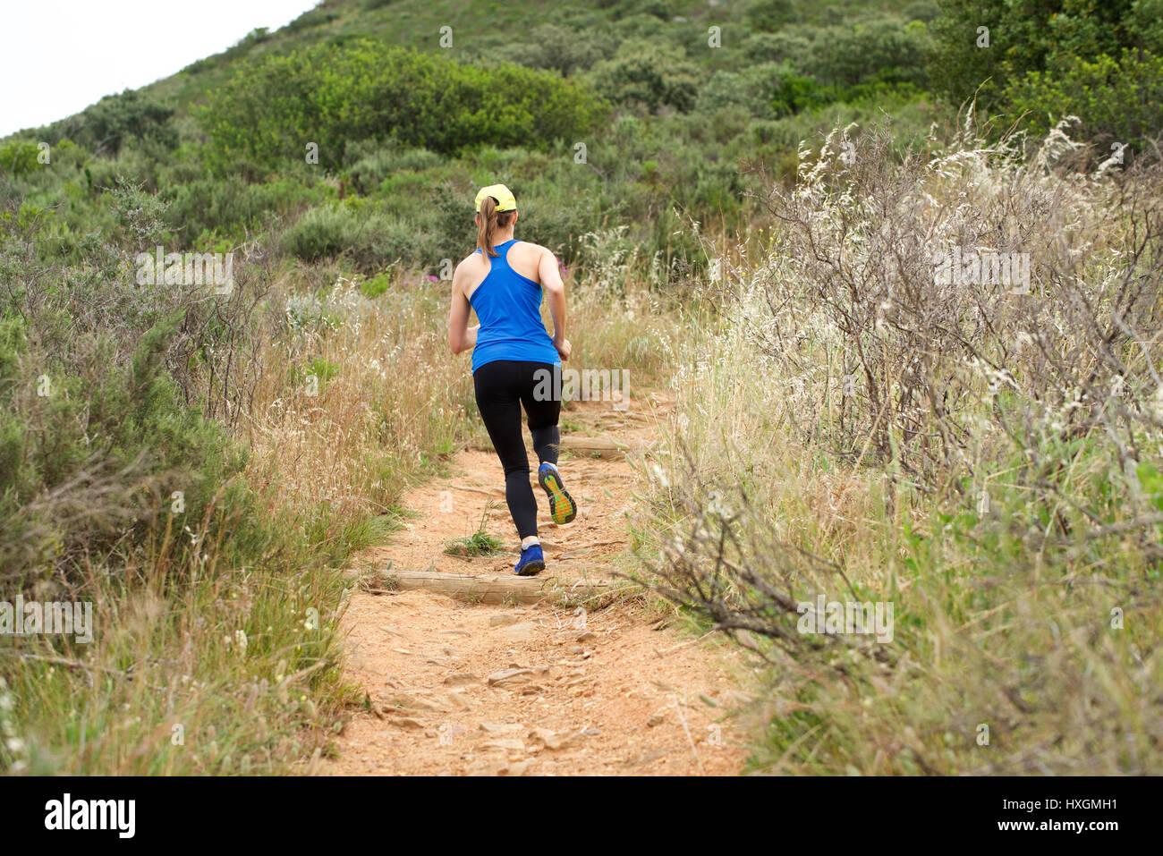 Full length portrait from behind of athletic woman running on dirt ...