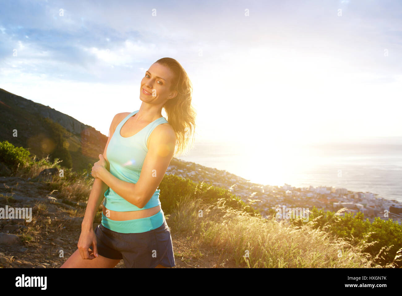 Portrait of beautiful fit woman standing outdoors at sunset Stock Photo ...