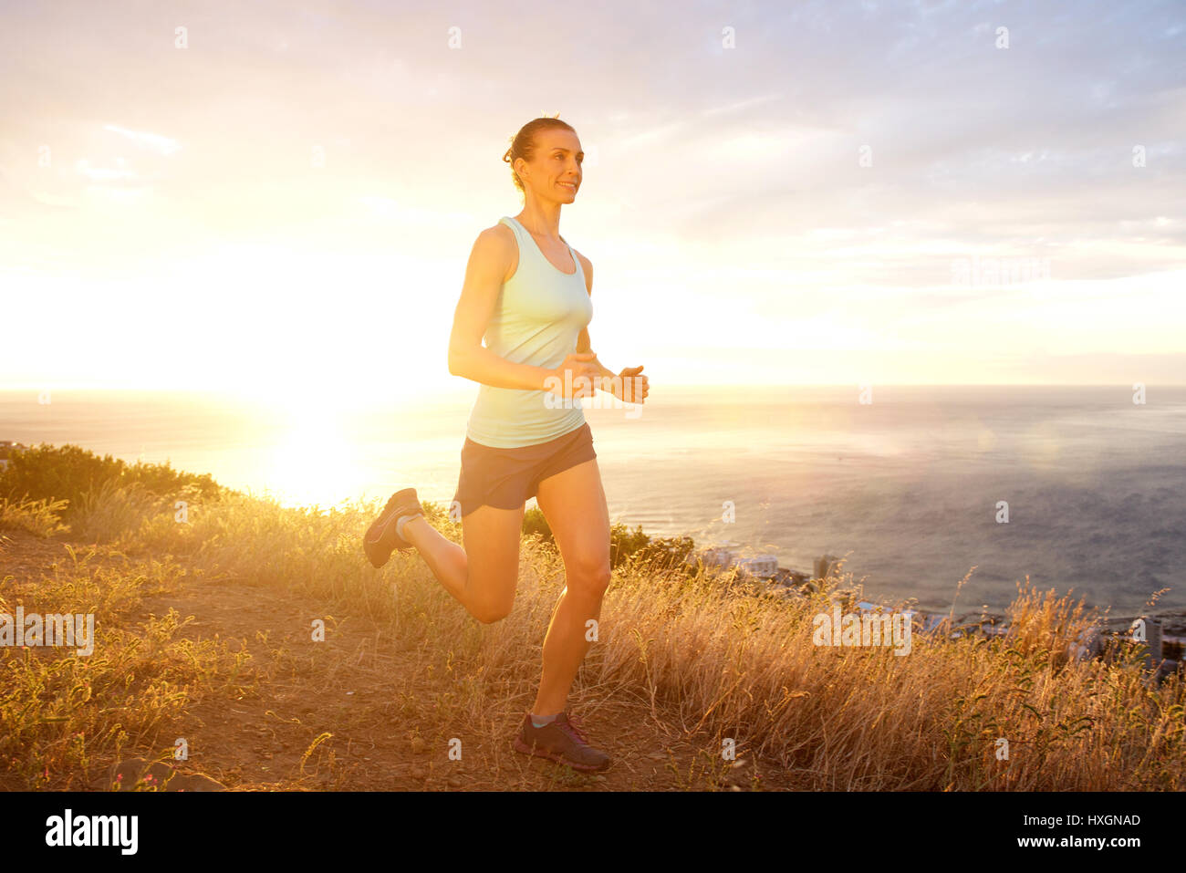 Full length portrait of active woman running outdoors during sunset ...