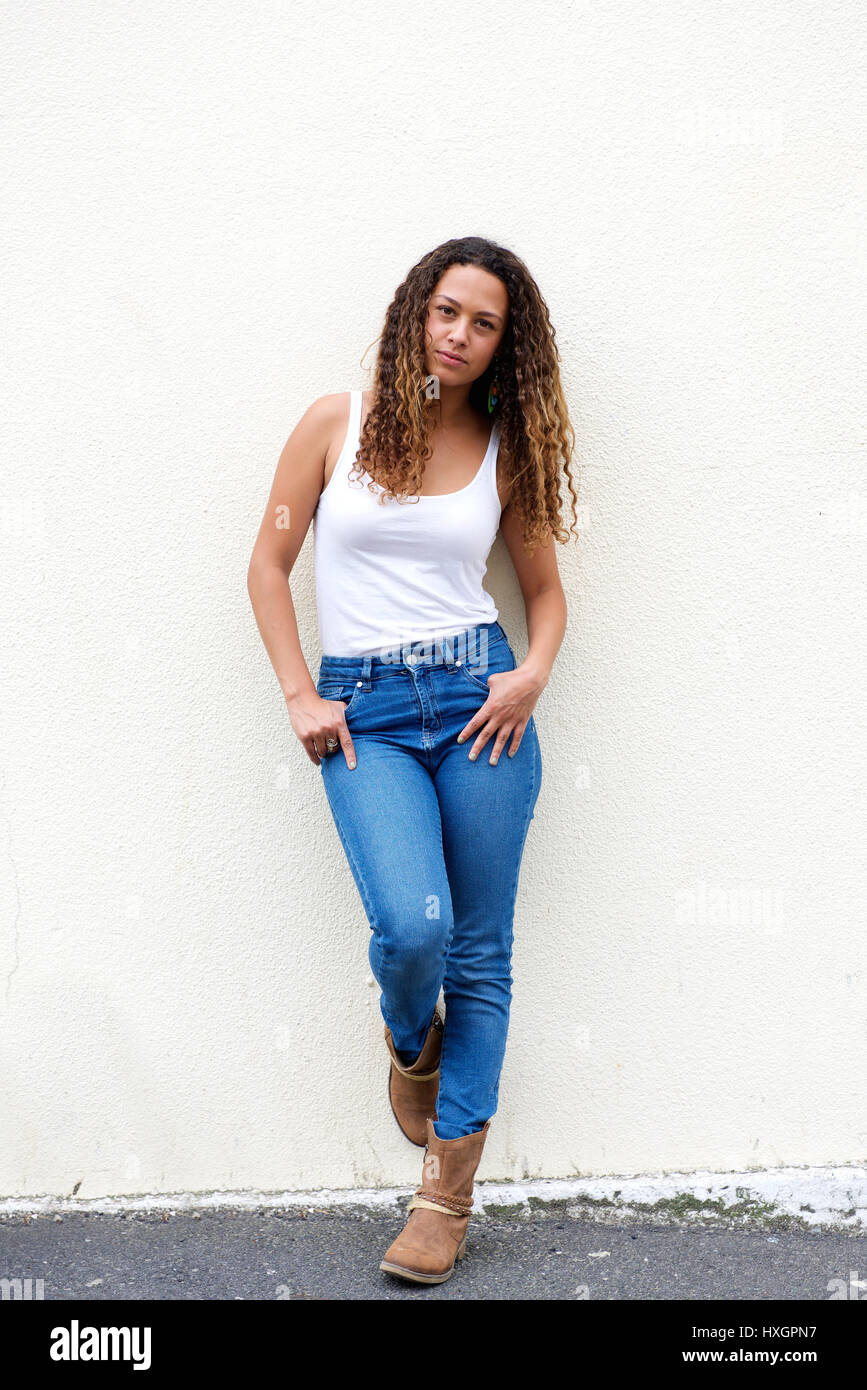 Full body cool young woman in jeans standing against white wall Stock ...