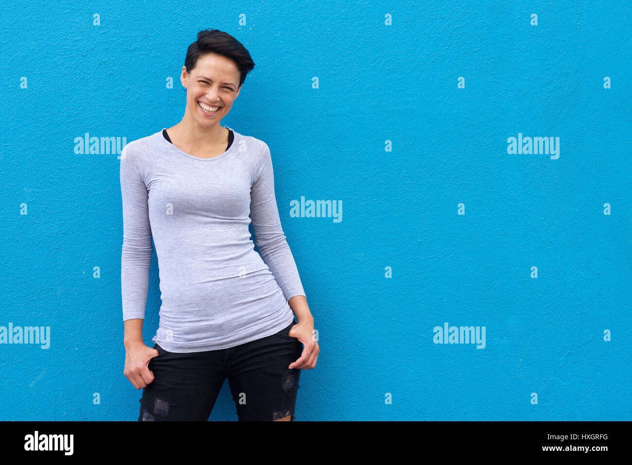 Portrait of a happy young woman smiling against blue background Stock ...