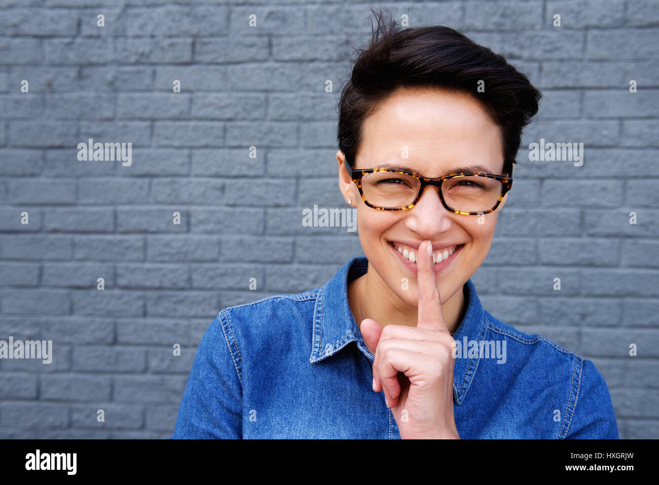 Close up portrait of a smiling woman with finger on lips Stock Photo ...