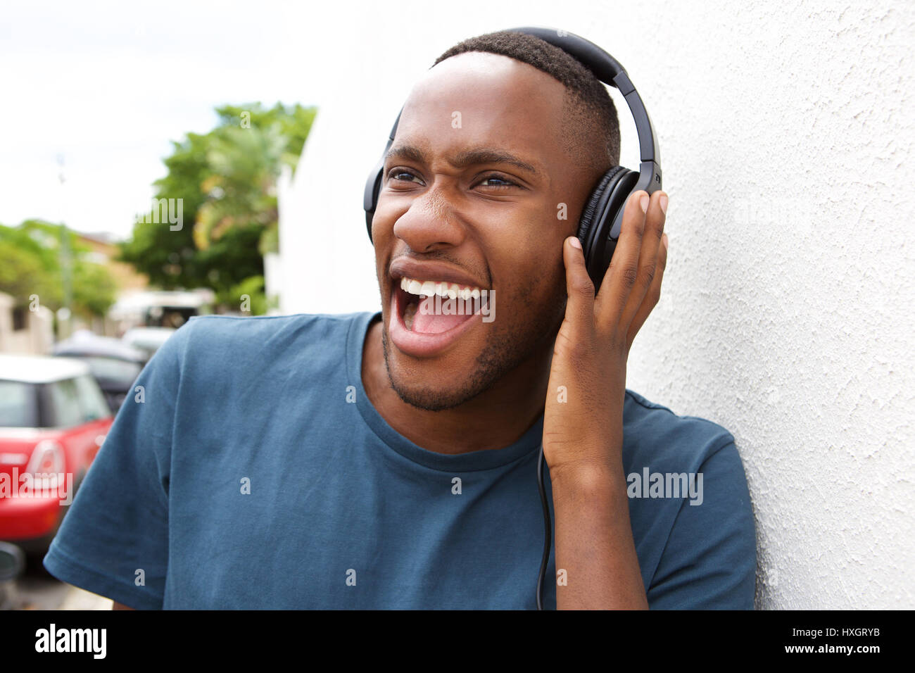 Portrait of a modern guy listening to music on headphones while ...