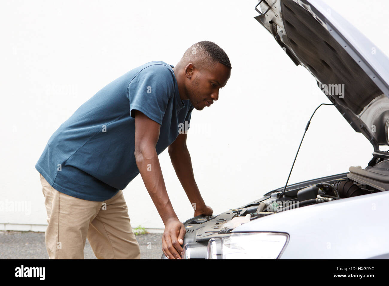 Side portrait of young african man looking under the hood of car Stock ...