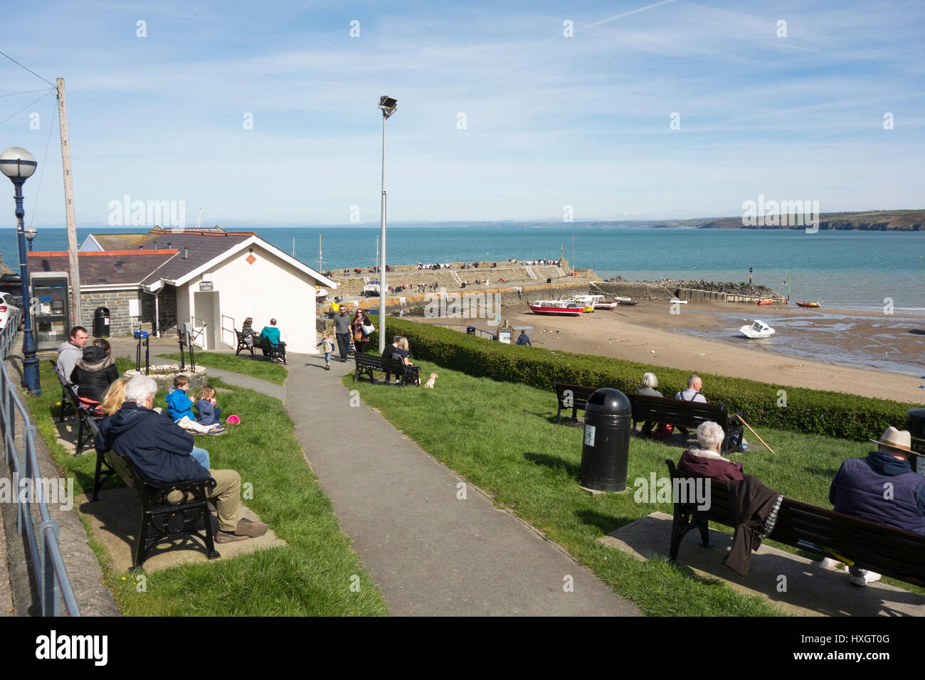Tourists sitting along the seafront in the small town of New Quay Wales ...