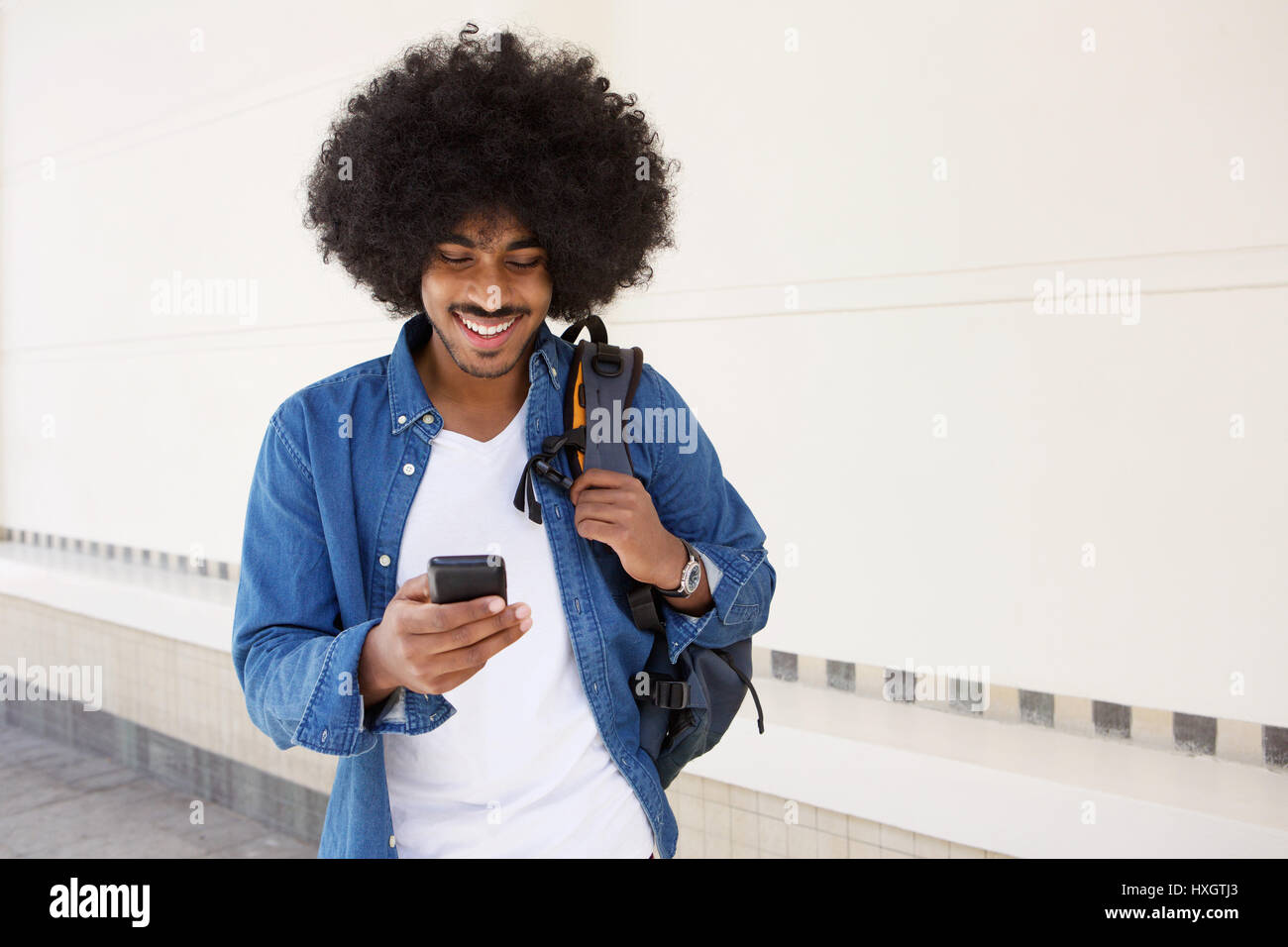 Portrait of a cool guy walking with mobile phone and bag Stock Photo ...