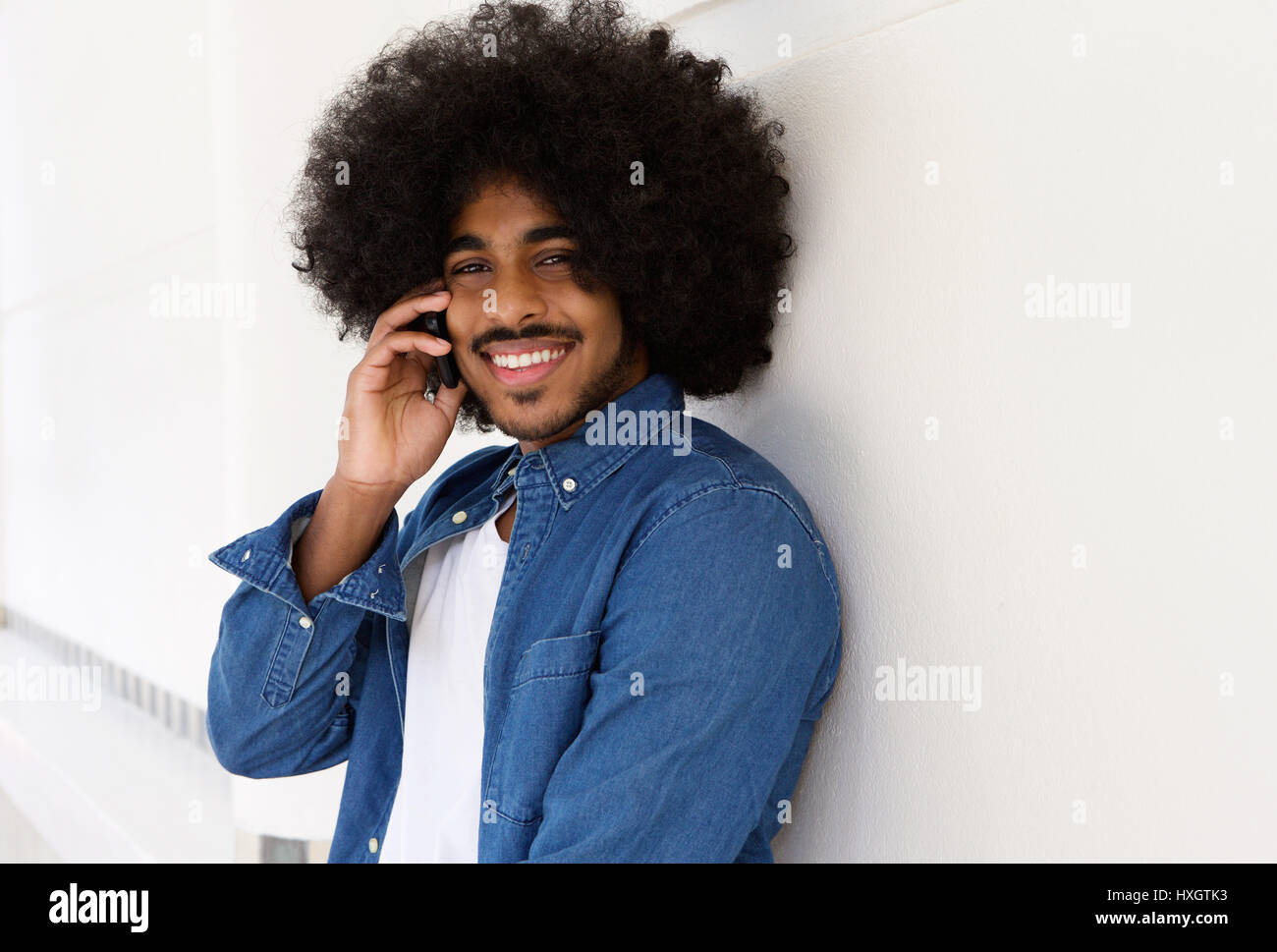 Portrait of a cool guy with afro using mobile phone Stock Photo - Alamy