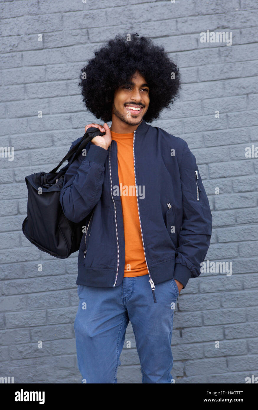 Portrait of a cool male fashion model with afro and bag Stock Photo - Alamy