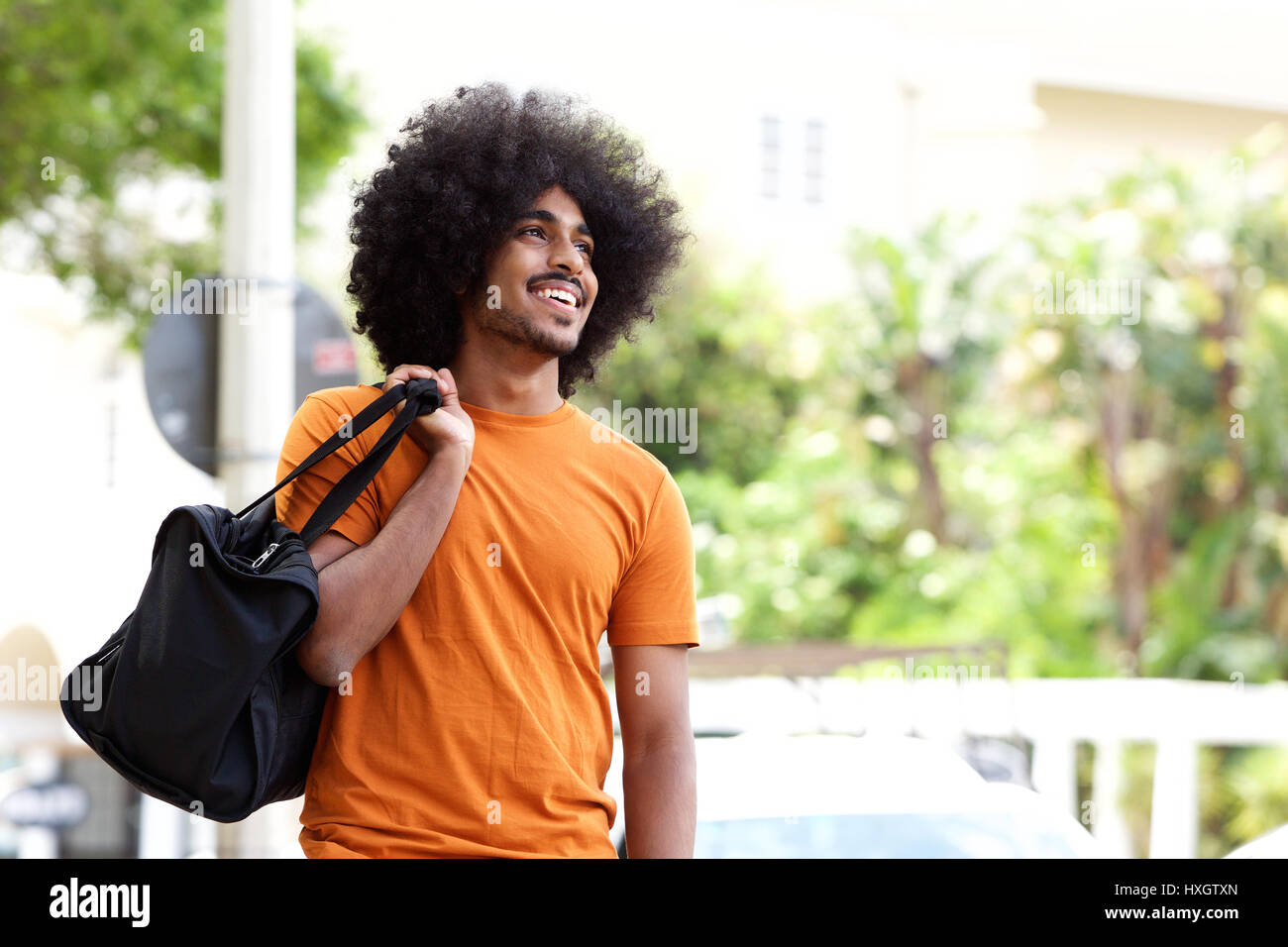 Portrait of a happy guy walking with bag outside Stock Photo - Alamy