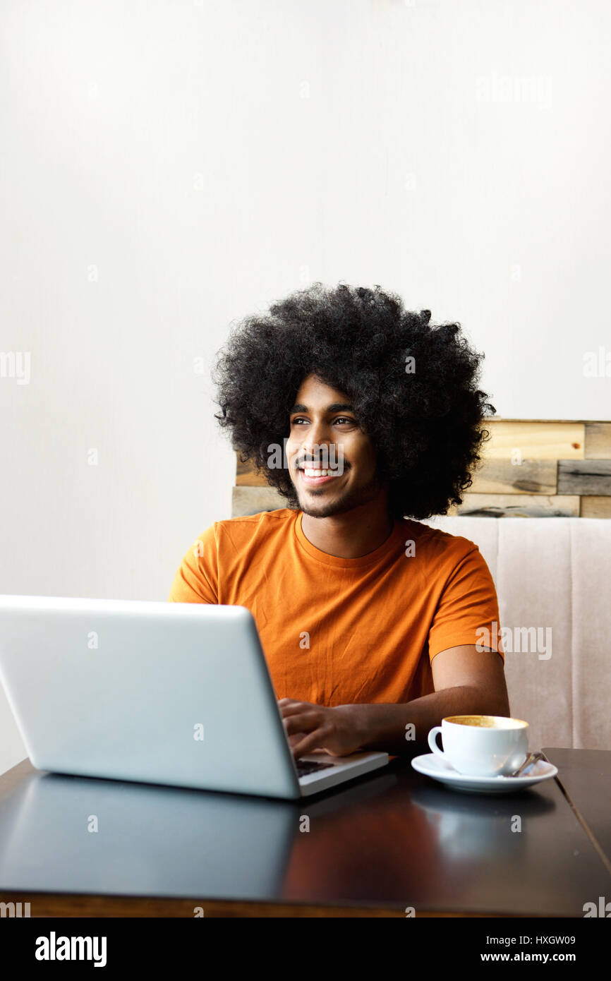 Portrait of a smiling man sitting at table with laptop Stock Photo - Alamy